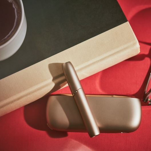 A golden IQOS kept on a notepad